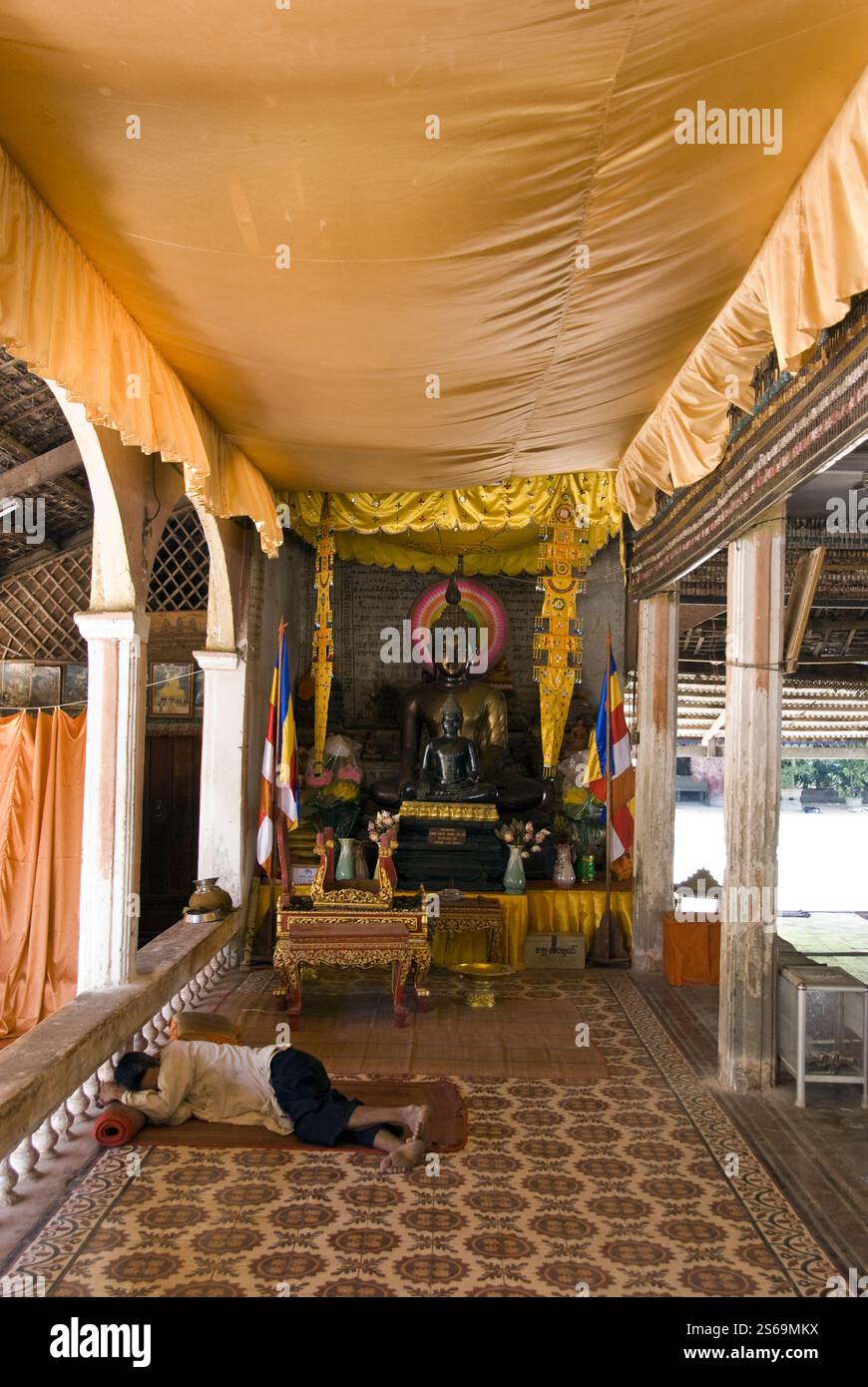 A man sleeps in front of altar at Wat Bo, one of the oldest Buddhist ...