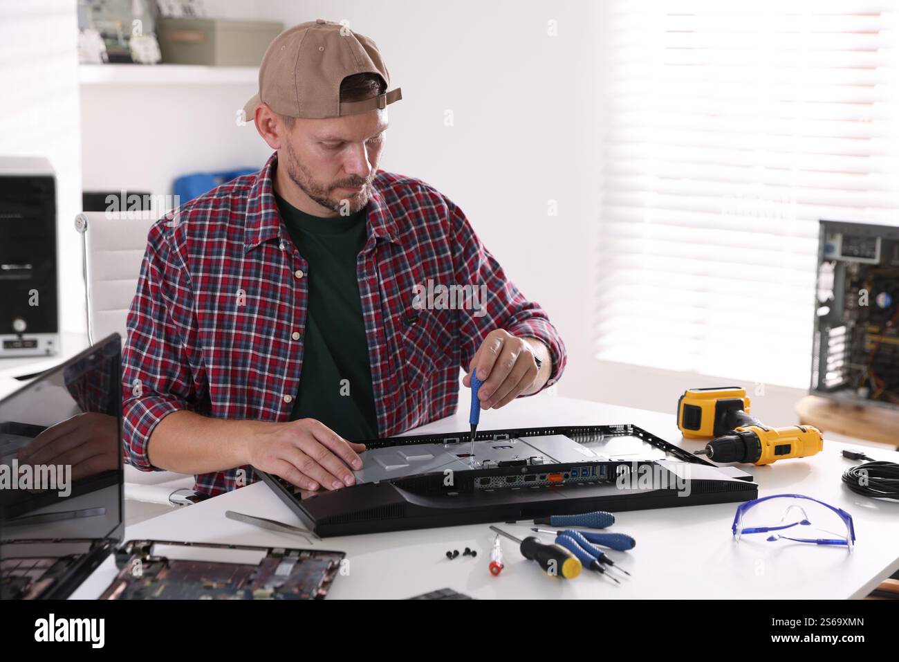 Man fixing computer monitor at white table Stock Photo - Alamy