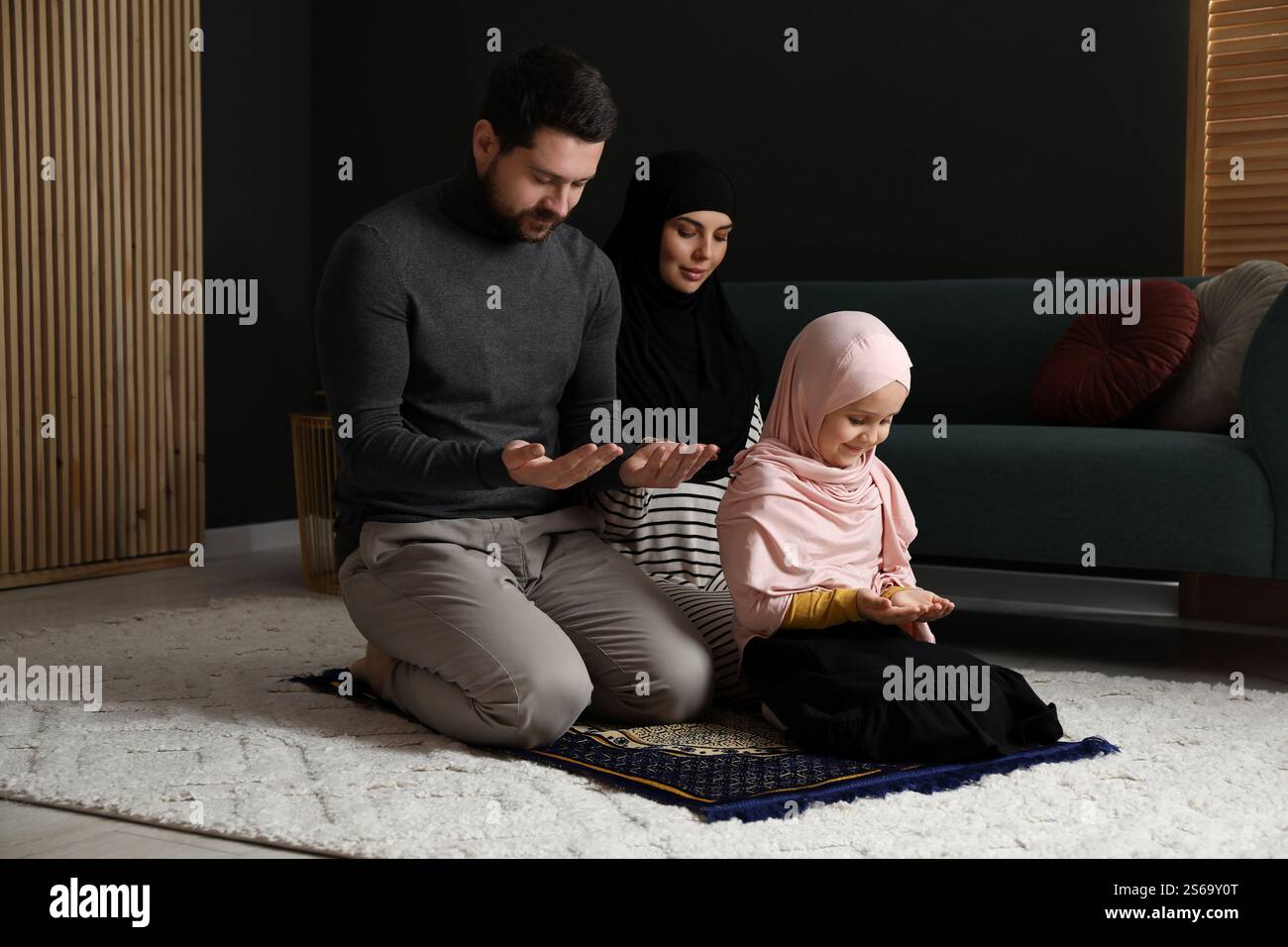 Muslim family praying on mat at home Stock Photo - Alamy