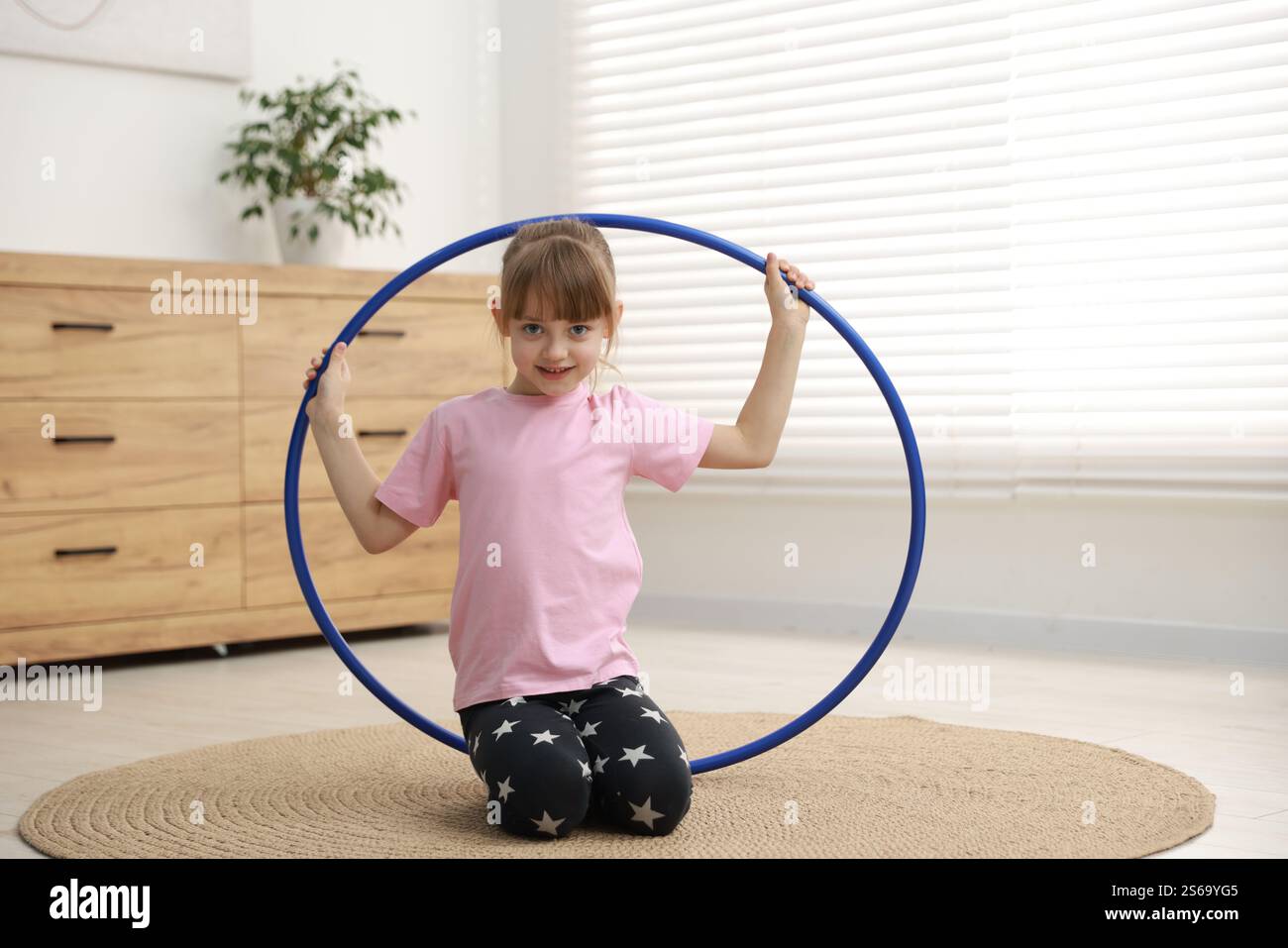 Cute little girl with hula hoop on floor at home Stock Photo - Alamy