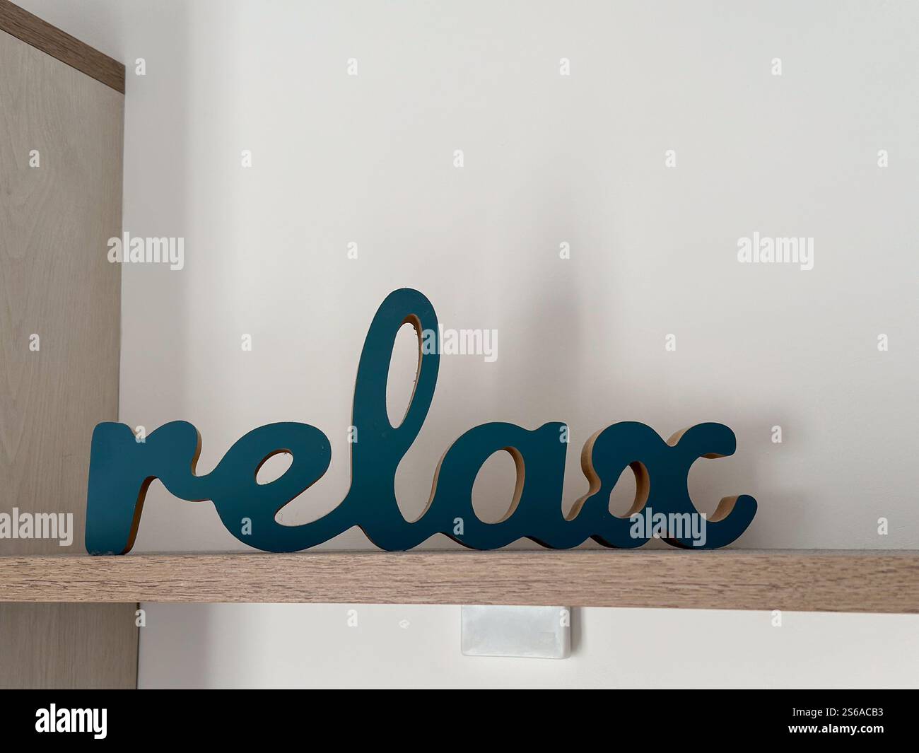 Decorative relax sign placed on a wooden shelf. The bold yet calming ...