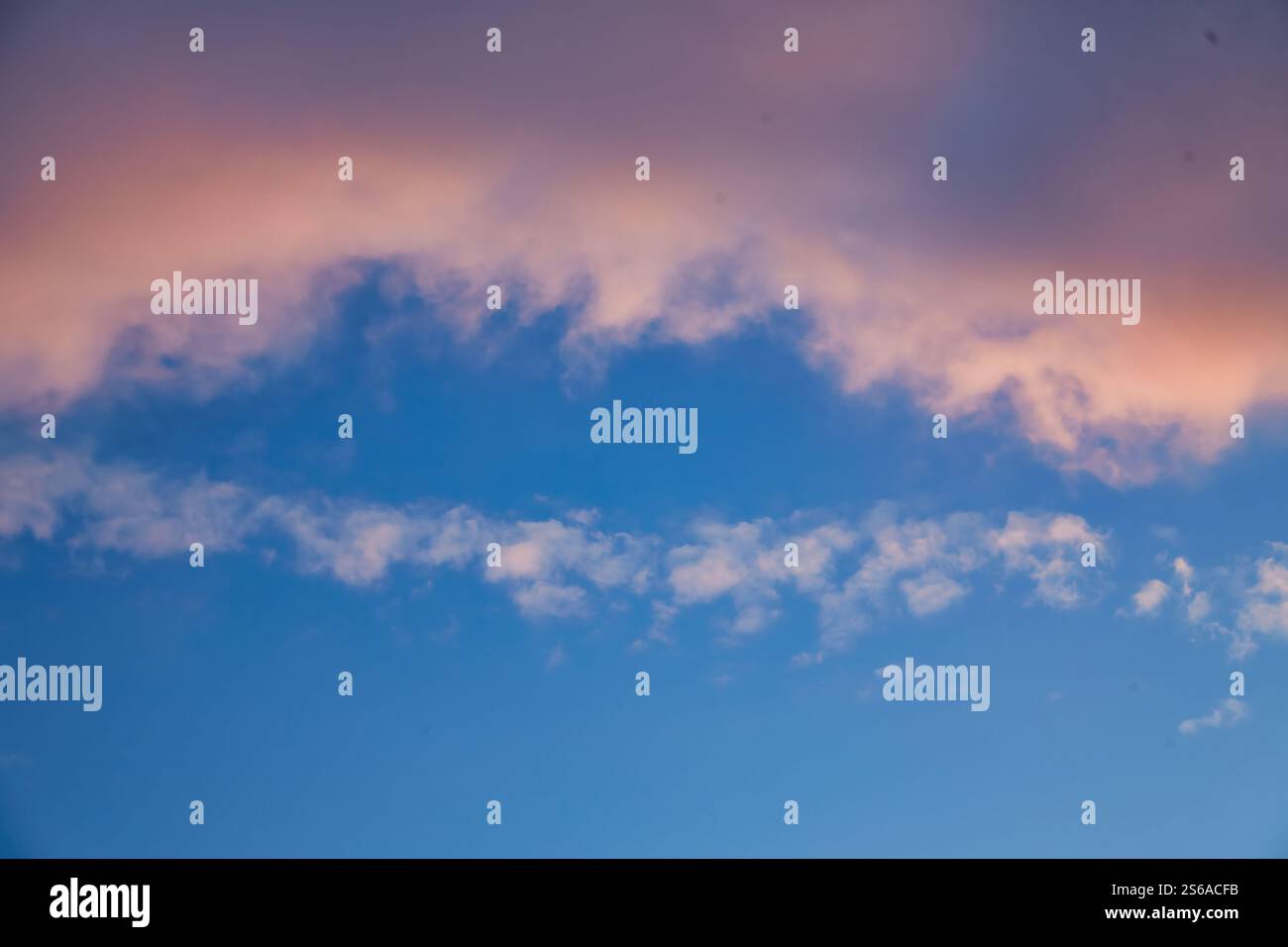 A calm sky with soft golden clouds illuminated by the setting sun. The ...