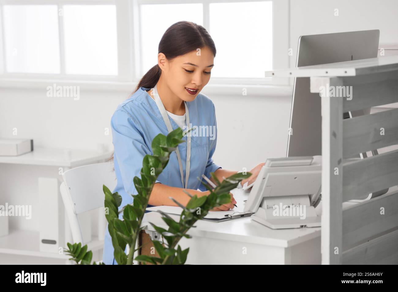 Female Asian medical intern working at reception in clinic Stock Photo ...