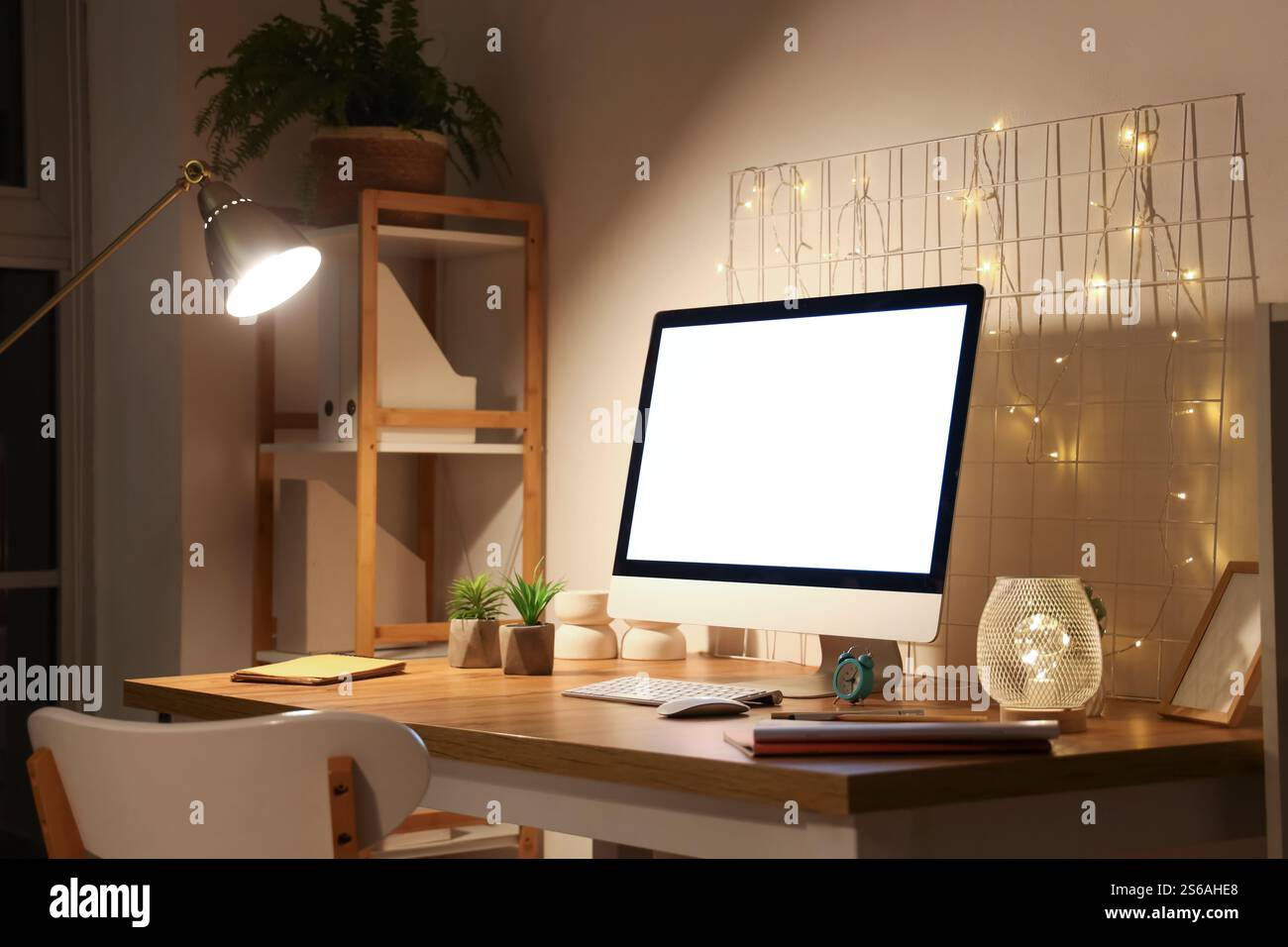 Workplace with blank computer monitor, pin board and glowing lights in ...