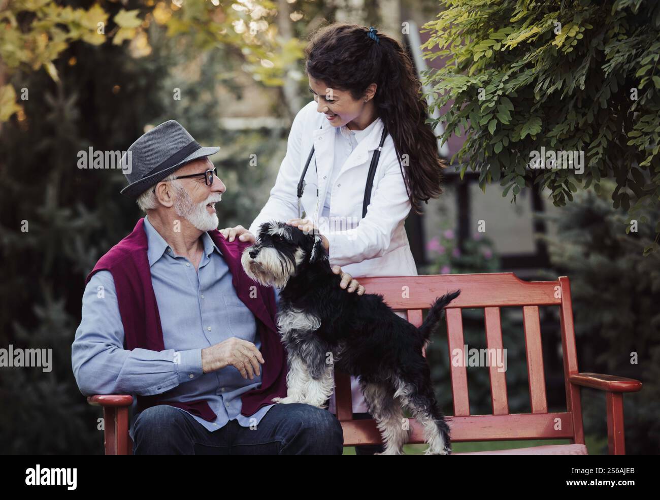 Pretty young nurse in white coat taking care of senior man in park ...