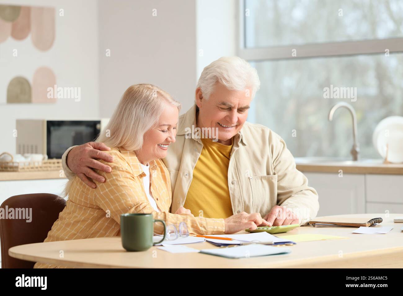 Senior woman with her husband calculating utility bills in kitchen ...