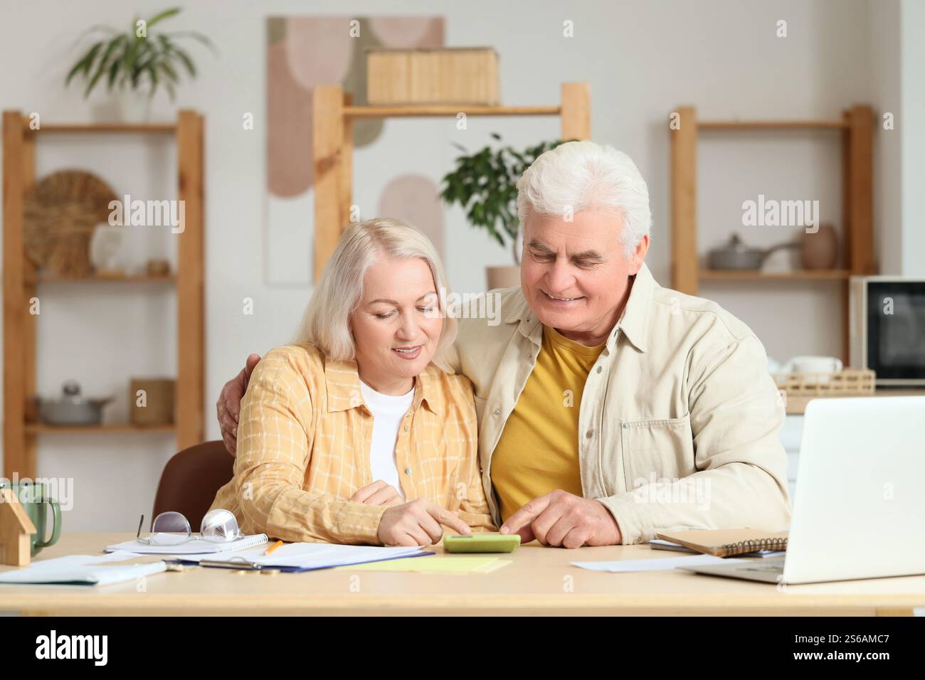 Senior woman with her husband calculating utility bills in kitchen ...