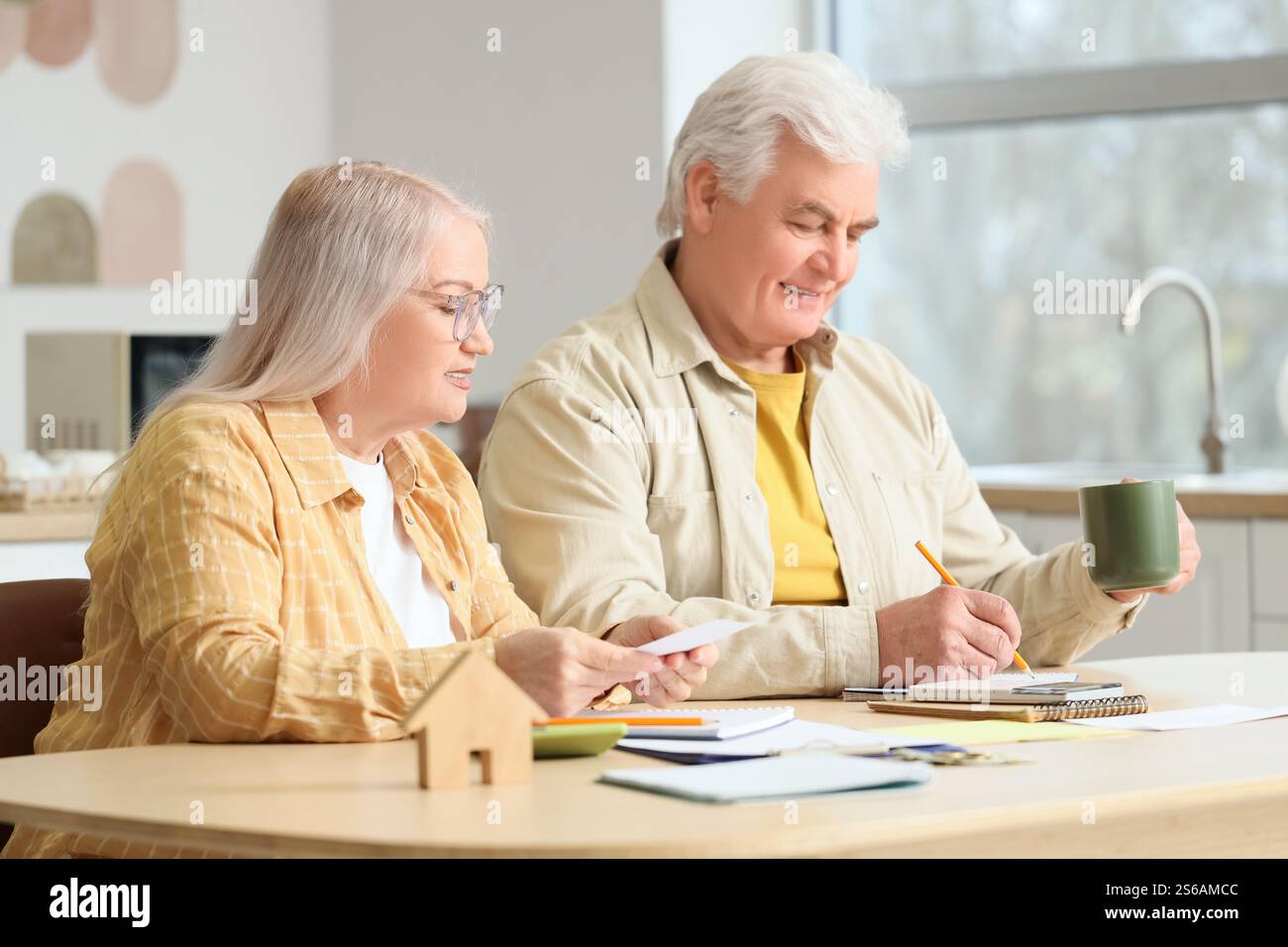 Senior woman with her husband calculating utility bills in kitchen ...
