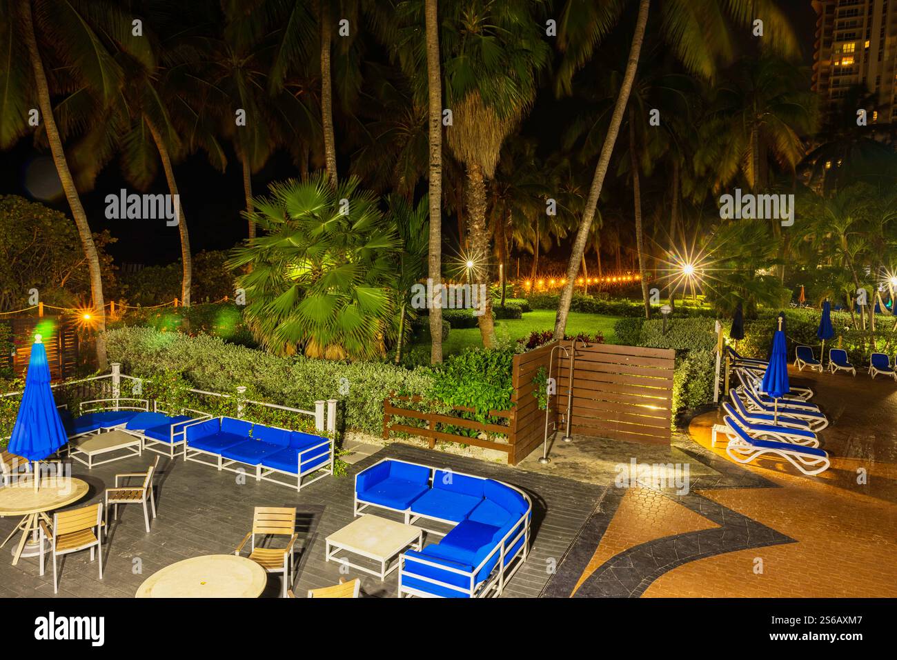 Illuminated tropical resort patio with lounge seating and blue sun ...