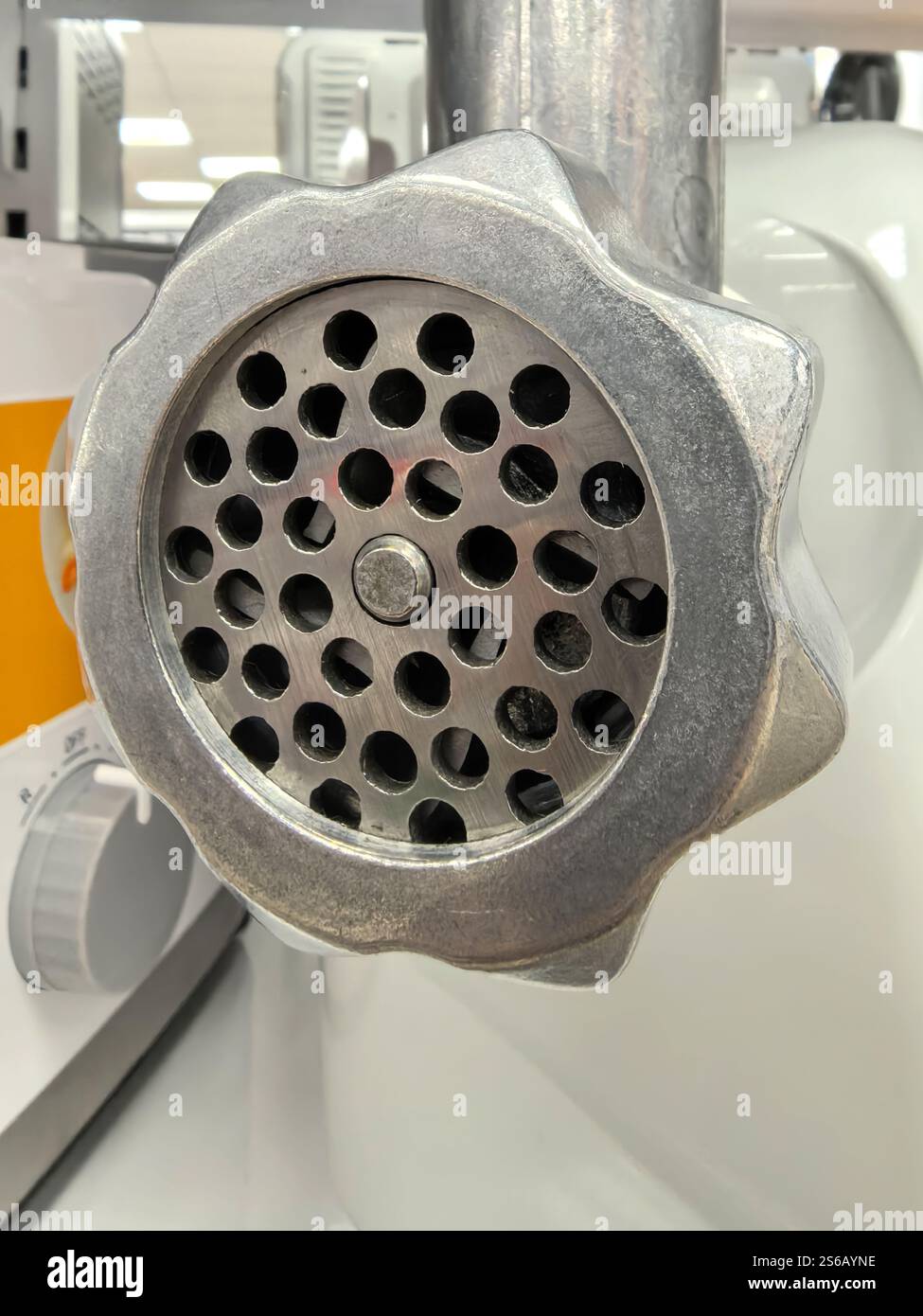 A close-up of a metal meat grinder's plate showcases its round holes ...