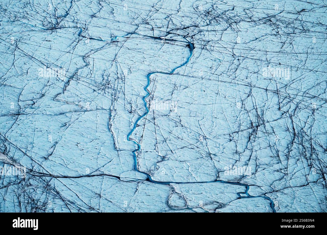 Glacier surface reveals intricate patterns and deep blue veins carved ...