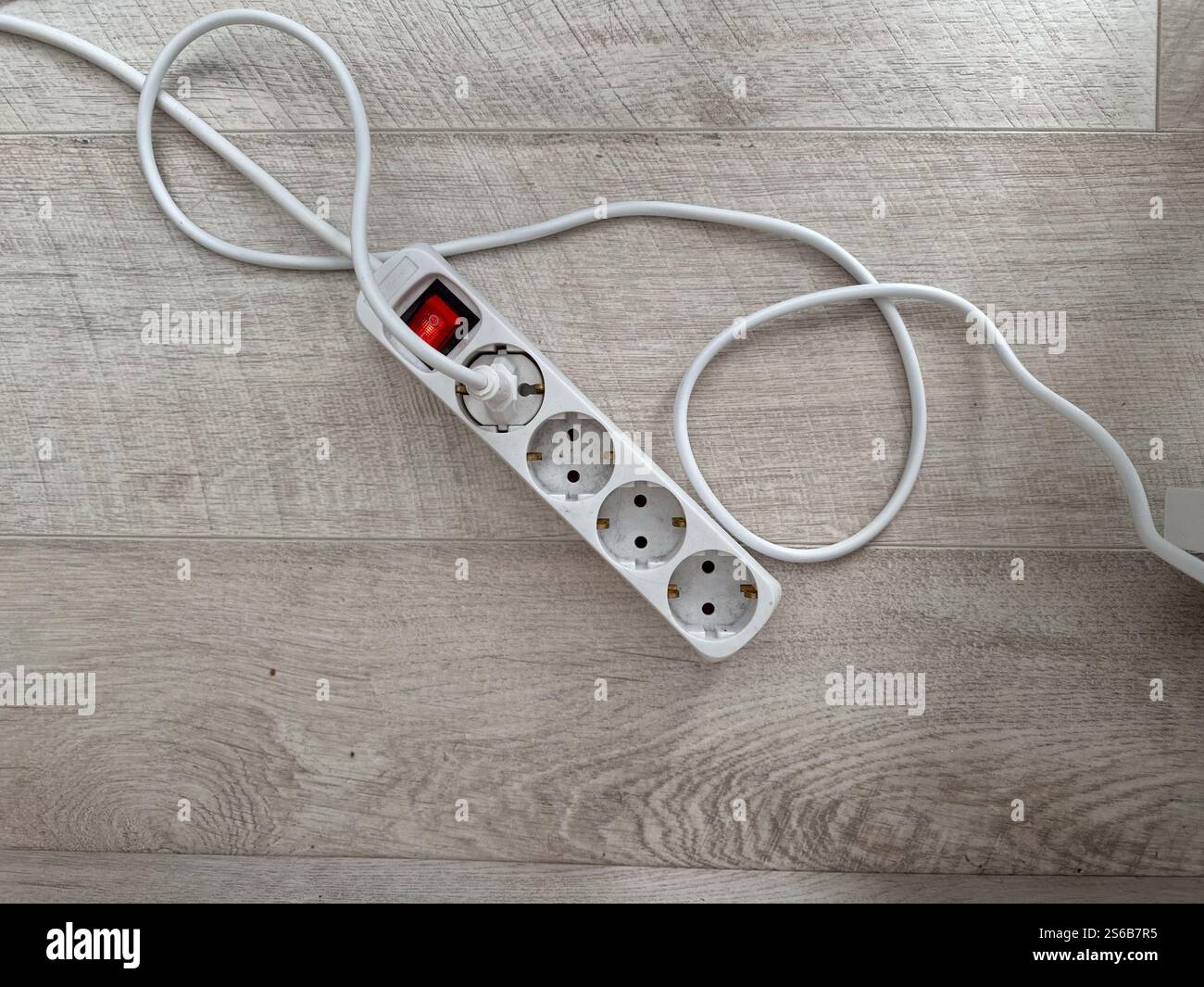 An extension cord with multiple outlets lying on a wooden floor ...