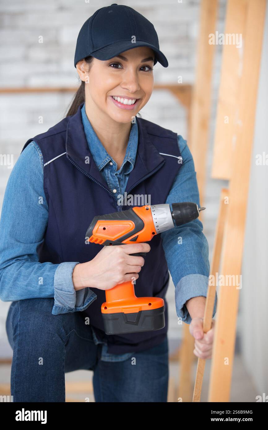 female worker using drill on wooden pieces Stock Photo - Alamy