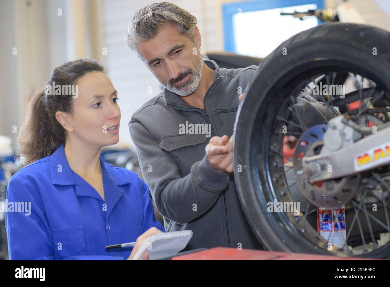 mechanic and female trainee working with tyre Stock Photo - Alamy