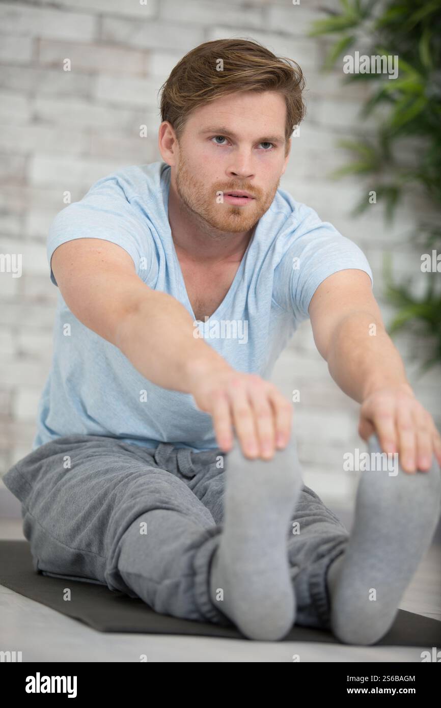 man touching his toes from sitting position stretching Stock Photo - Alamy