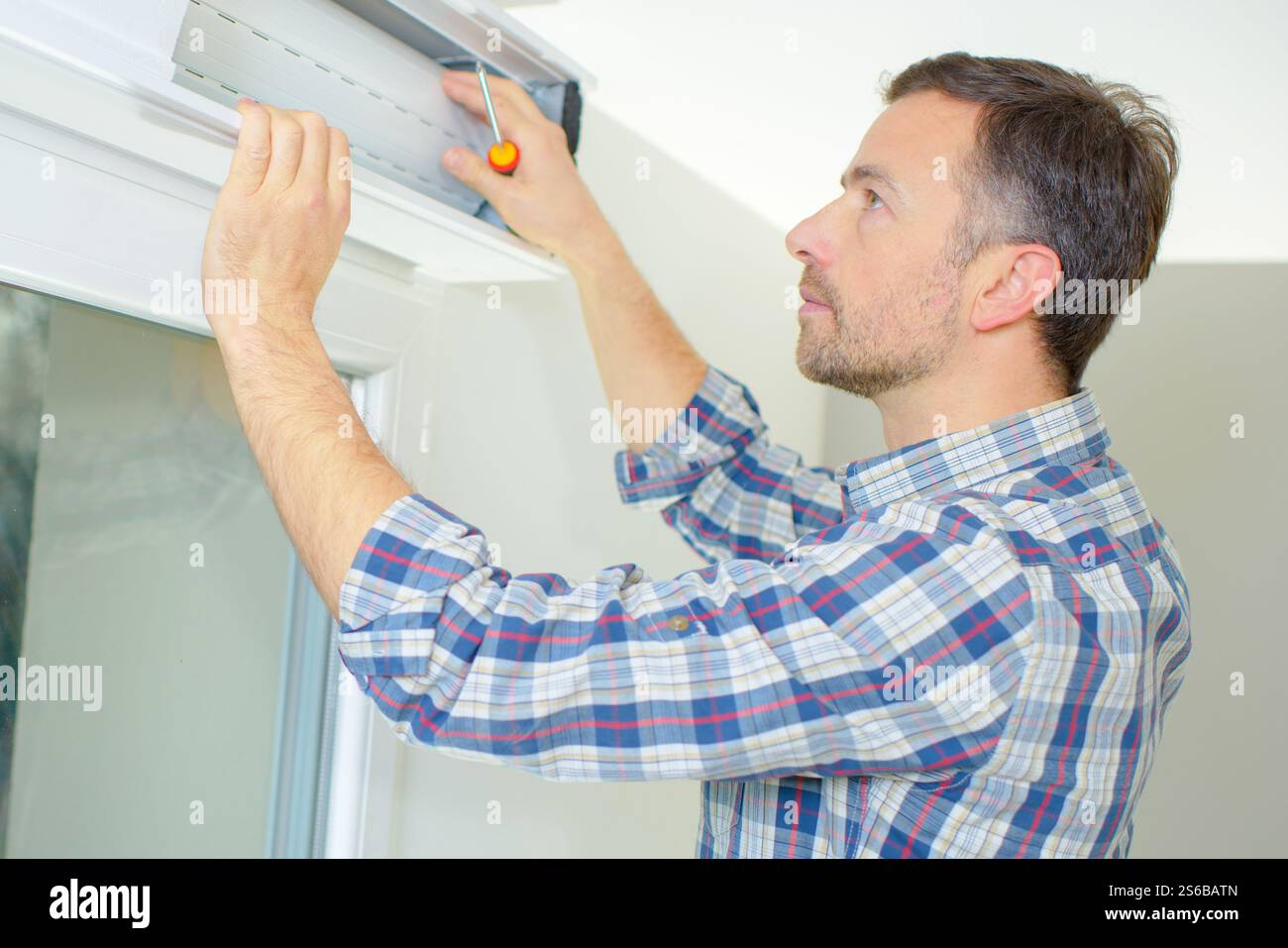 Builder working on roller shutter door Stock Photo - Alamy