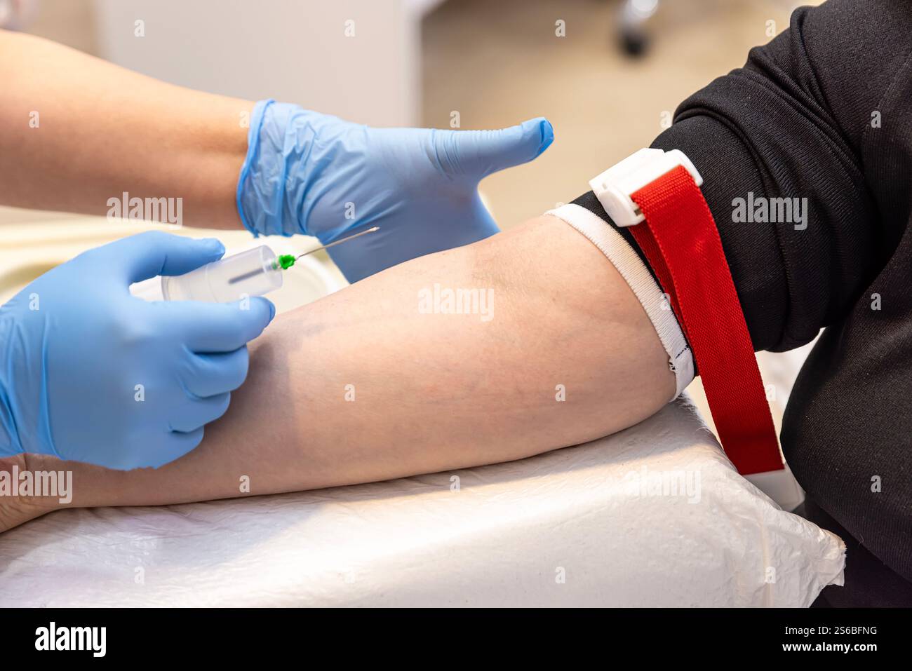 Doctor or nurse taking a blood sample from arm vein with a vacutainer ...