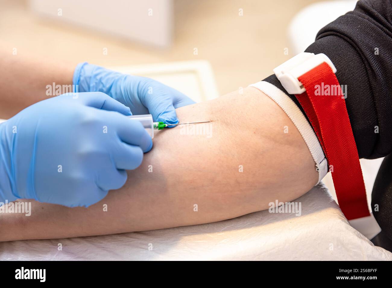 Doctor or nurse taking a blood sample from arm vein with a vacutainer ...