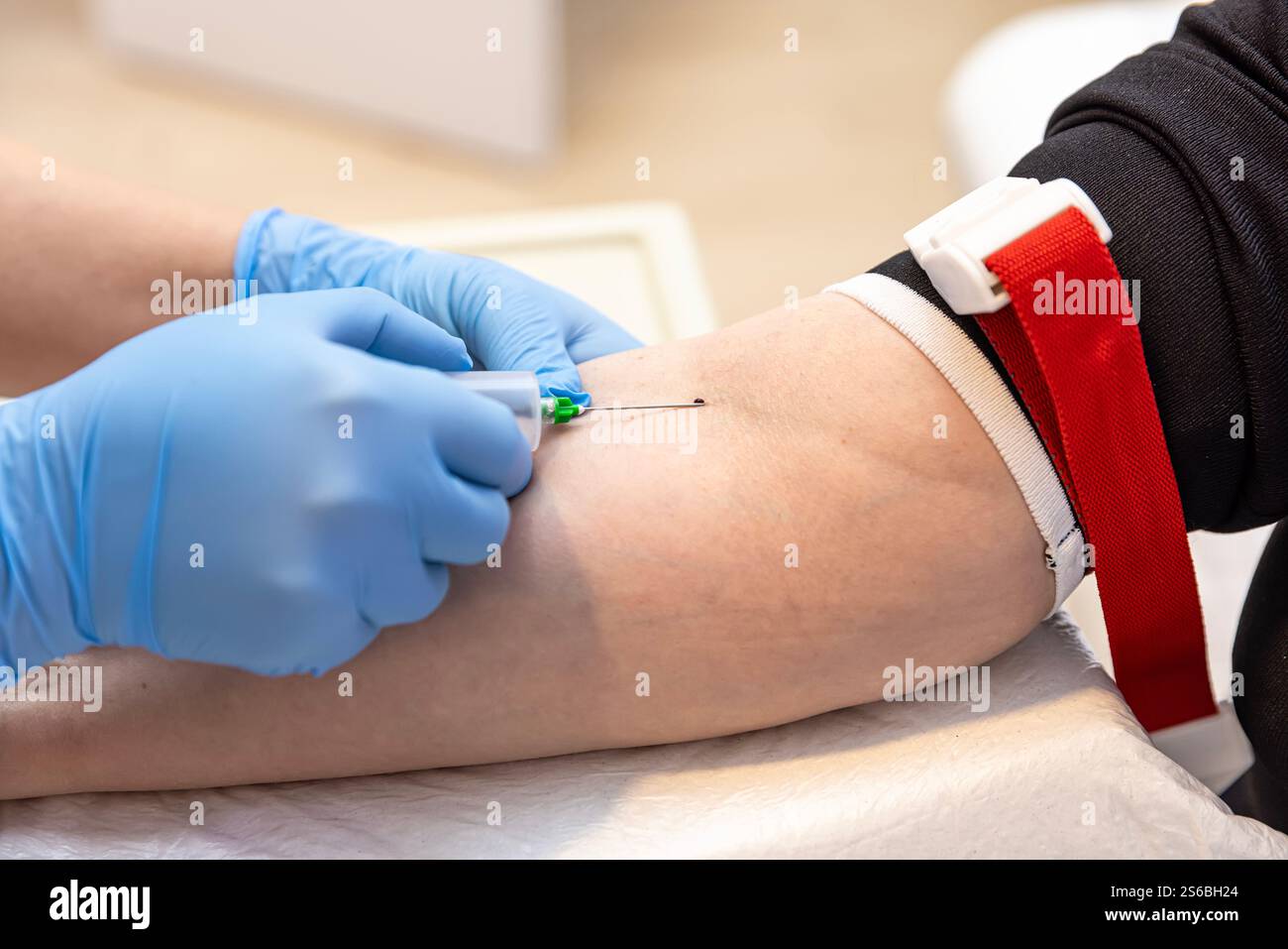 Doctor or nurse taking a blood sample from arm vein with a vacutainer ...