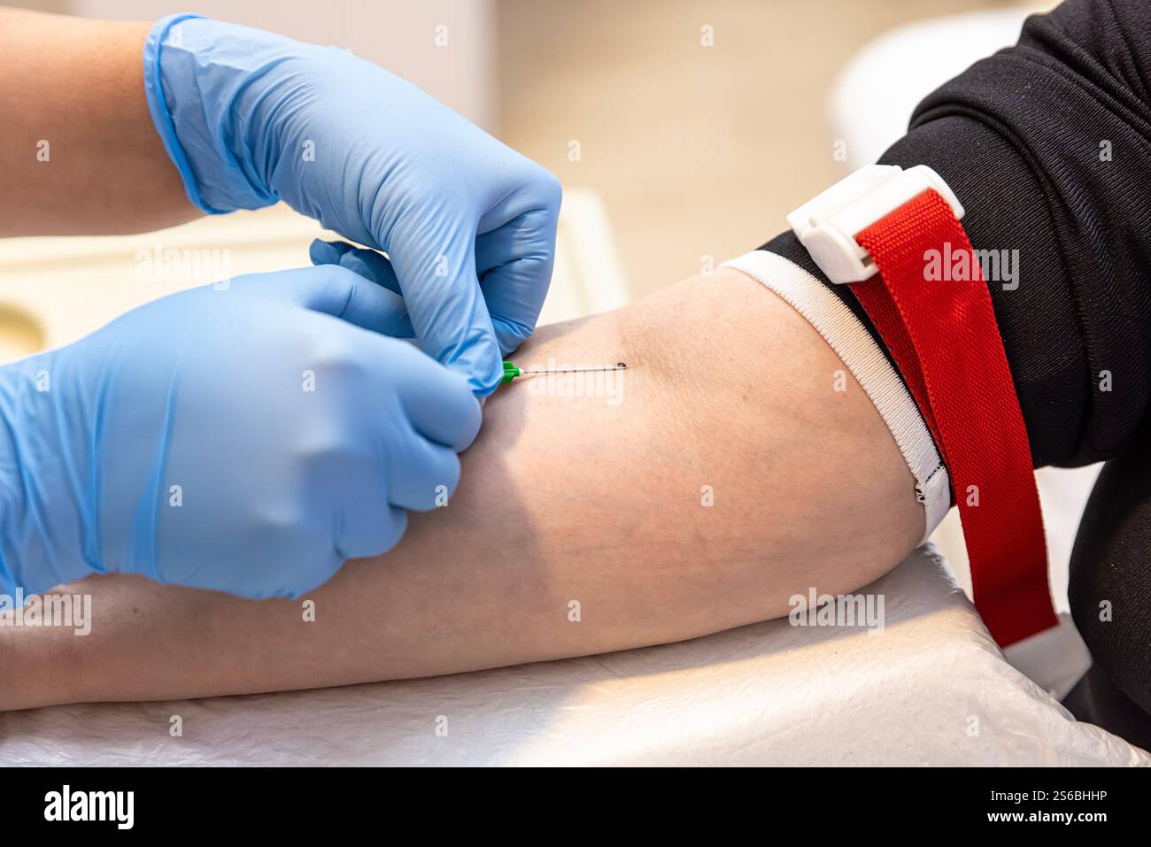 Doctor or nurse taking a blood sample from arm vein with a vacutainer. Venipuncture or ...