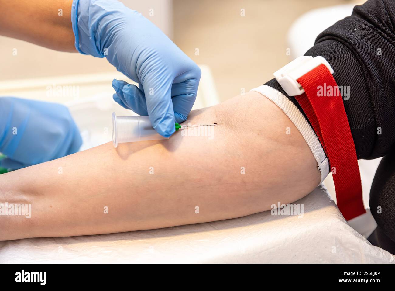 Doctor or nurse taking a blood sample from arm vein with a vacutainer ...