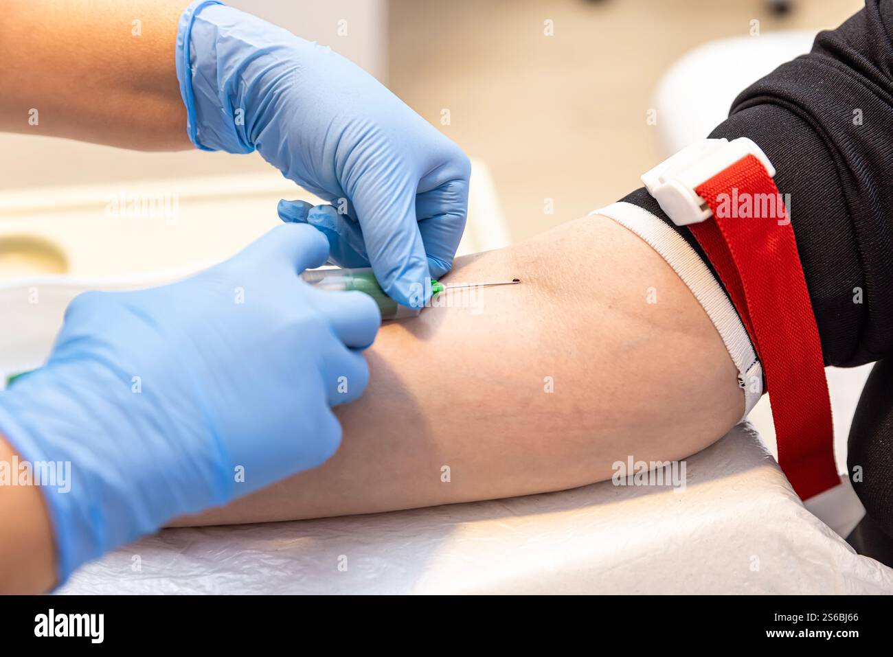 Doctor or nurse taking a blood sample from arm vein with a vacutainer ...