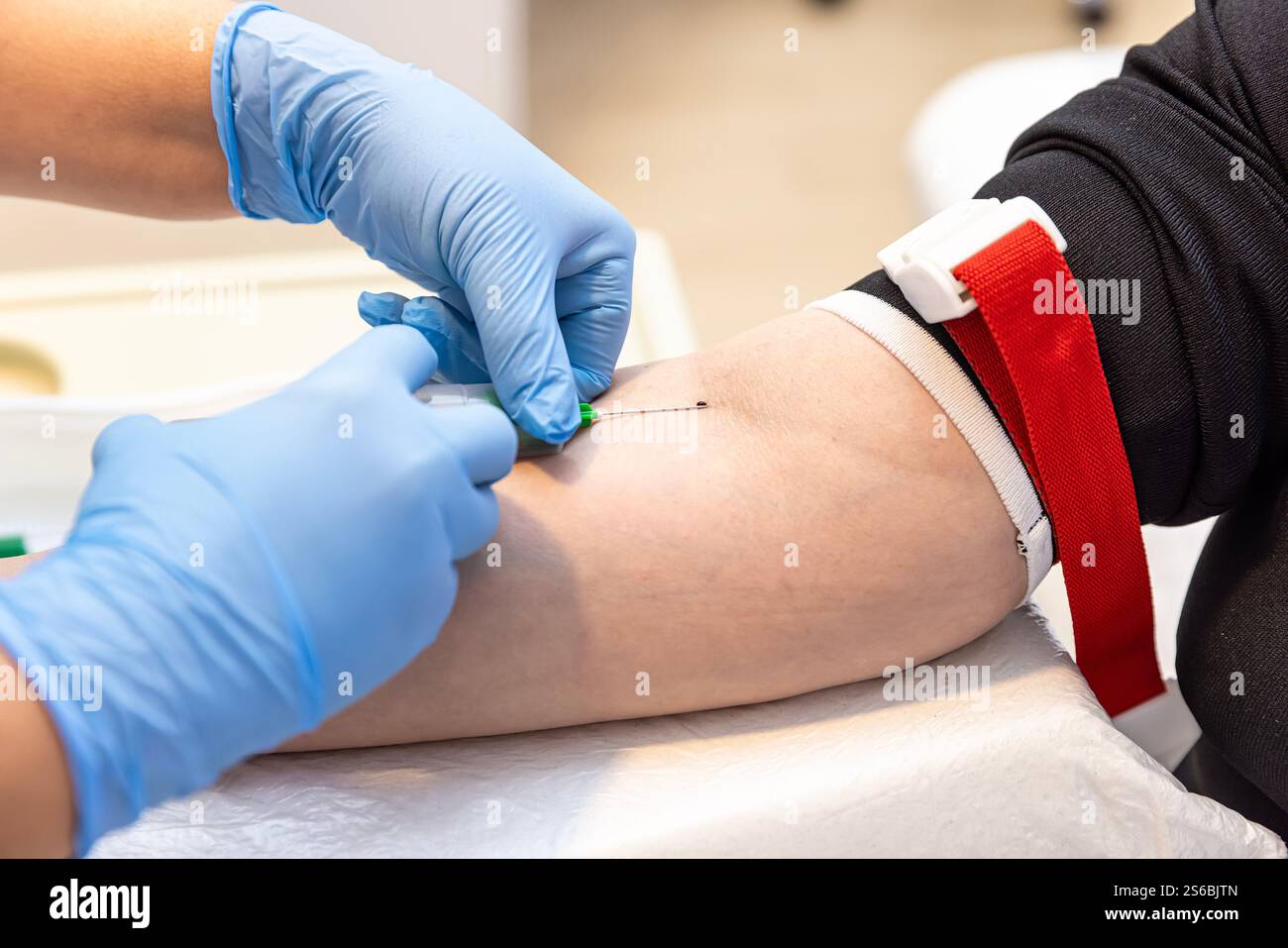 Doctor or nurse taking a blood sample from arm vein with a vacutainer. Venipuncture or ...