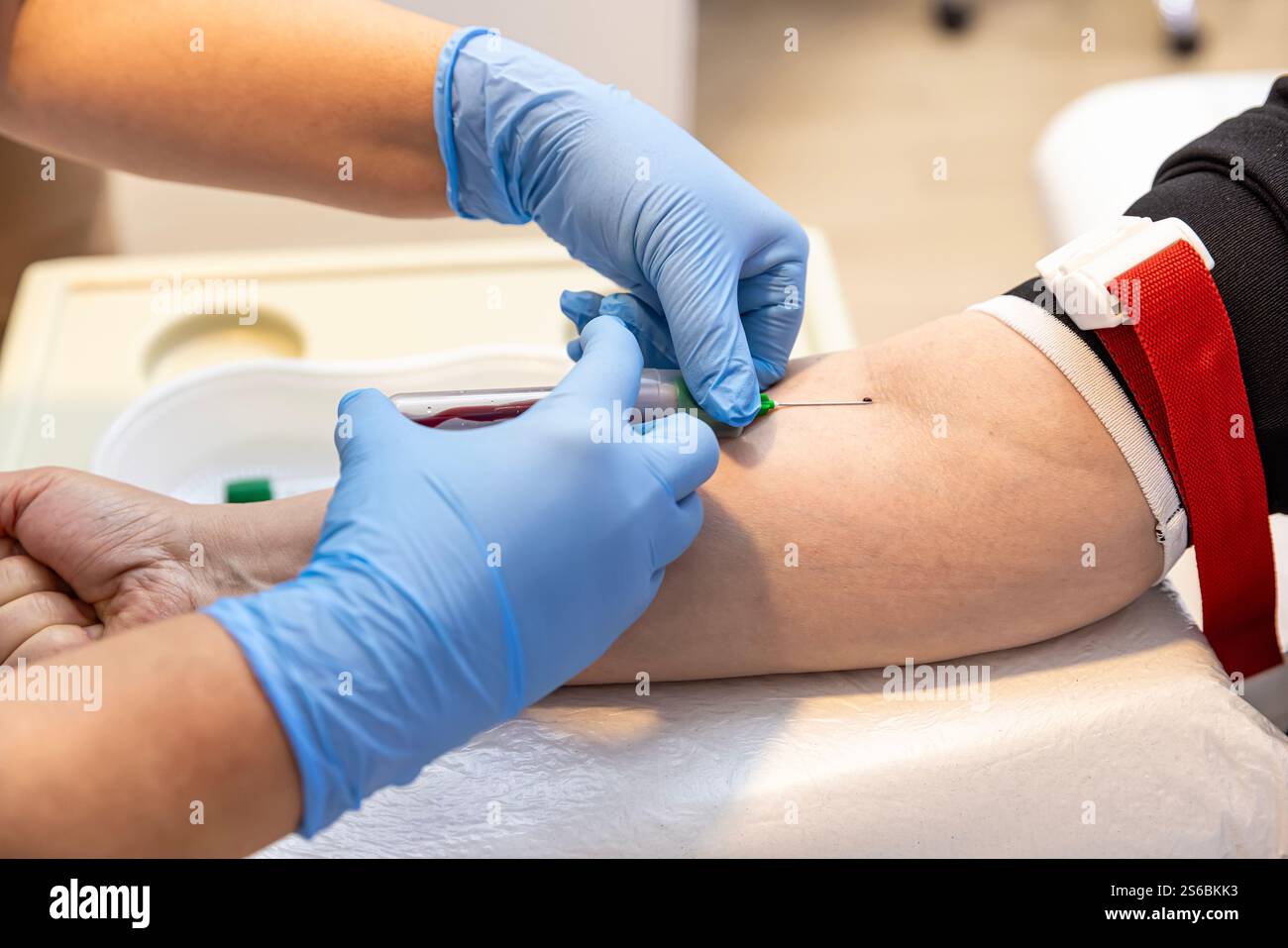 Doctor or nurse taking a blood sample from arm vein with a vacutainer ...