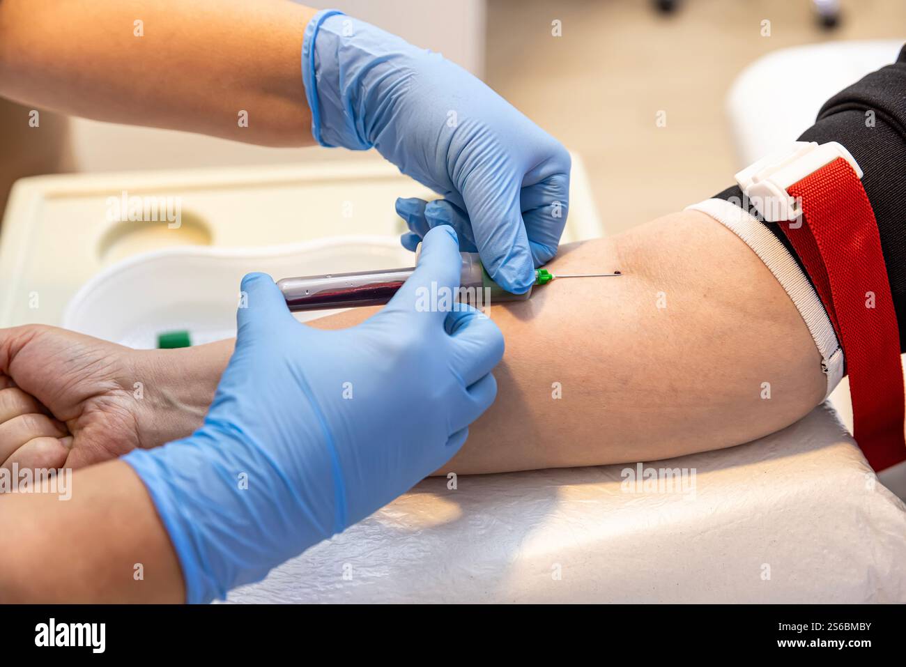 Doctor or nurse taking a blood sample from arm vein with a vacutainer ...