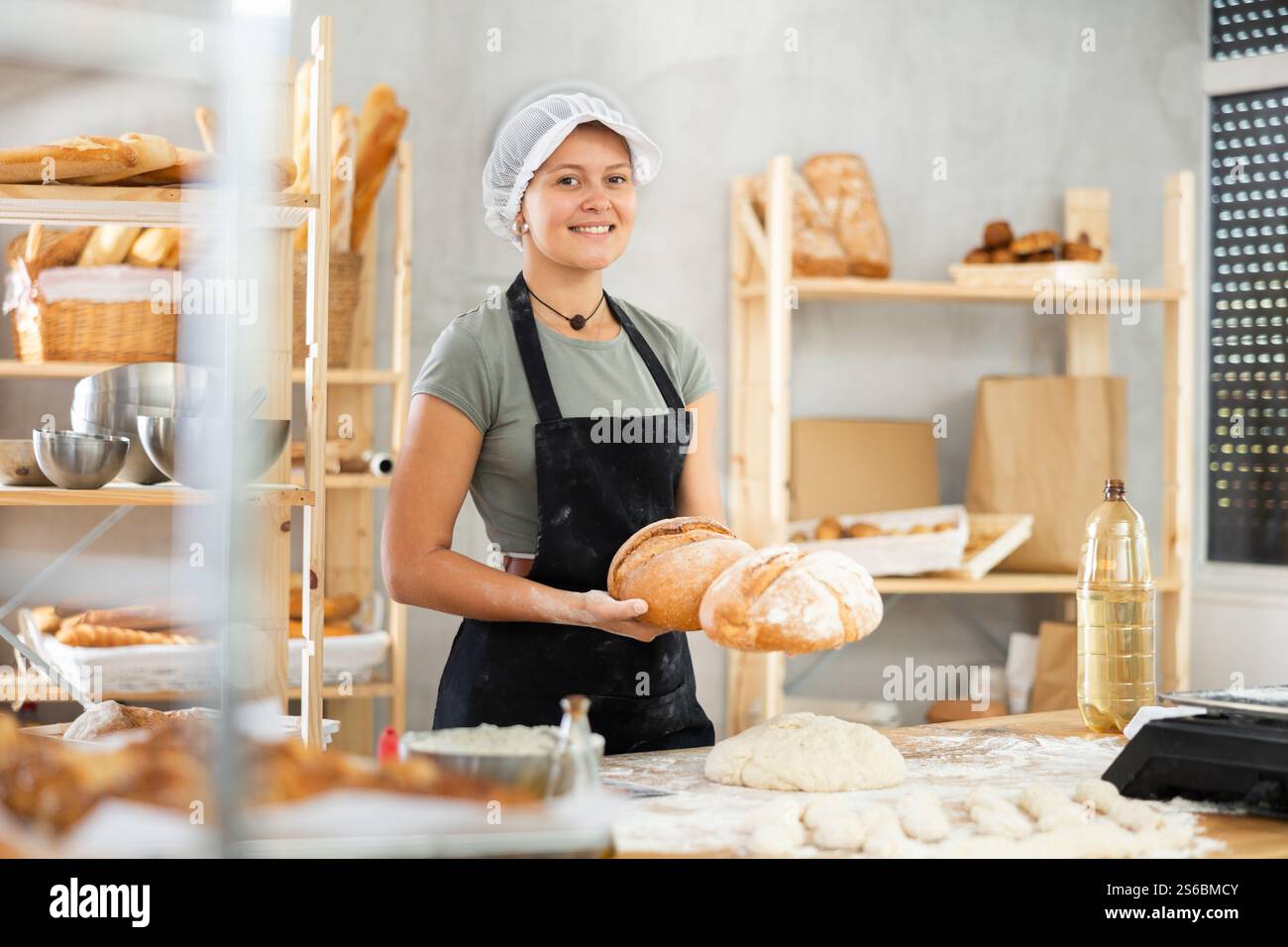 Bakery woman employee holds ready made bread of bread Stock Photo - Alamy