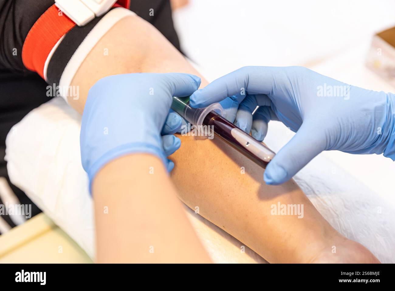 Doctor or nurse taking a blood sample from arm vein with a vacutainer. Venipuncture or ...