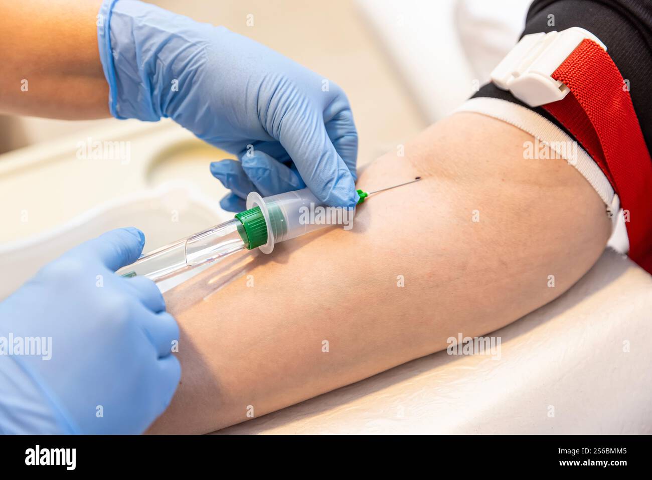 Doctor or nurse taking a blood sample from arm vein with a vacutainer ...