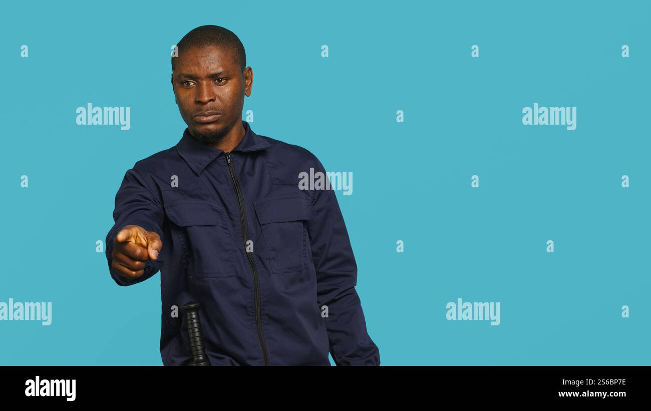 Portrait of security guard pointing finger at intruders while ...