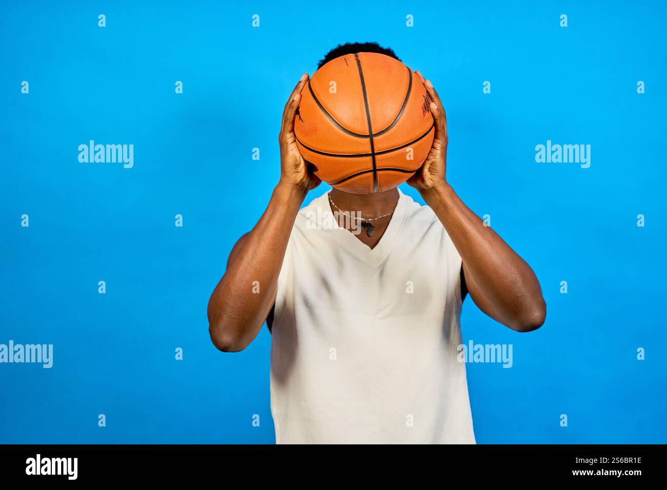 Athlete is holding a basketball in front of his face, obscuring his ...