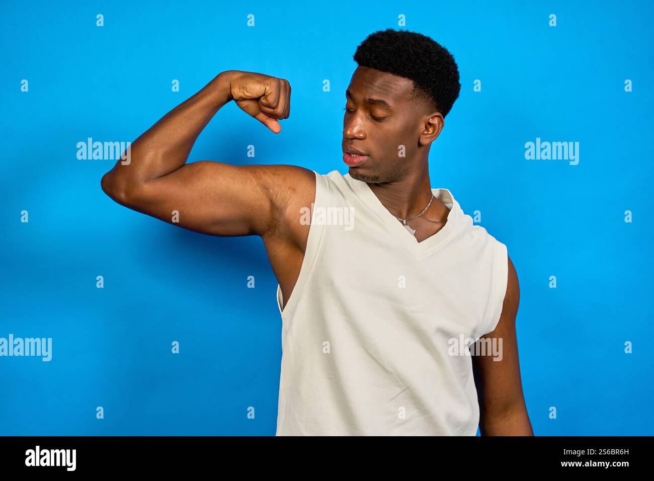 Athletic young man flexing his biceps while looking at his arm on a ...