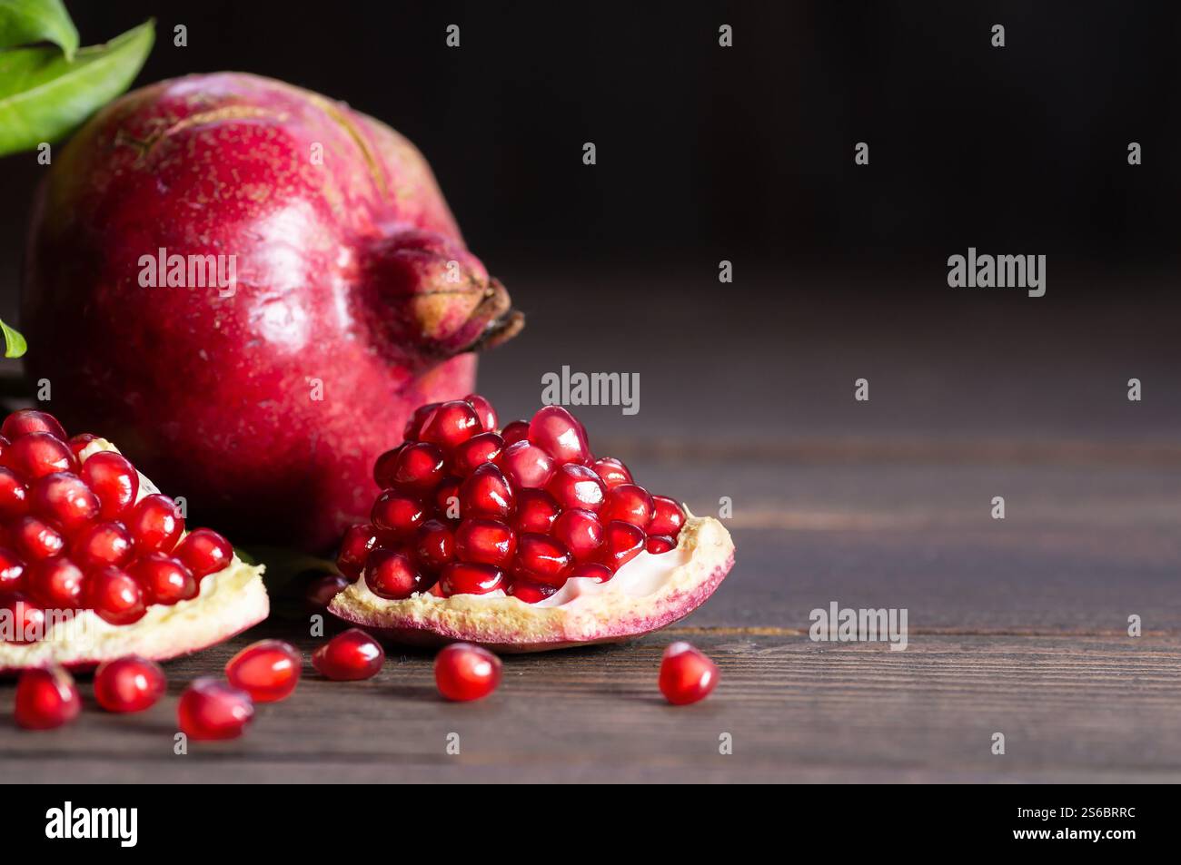 Fresh ripe whole and split juicy pomegranate with seeds and leaves on ...