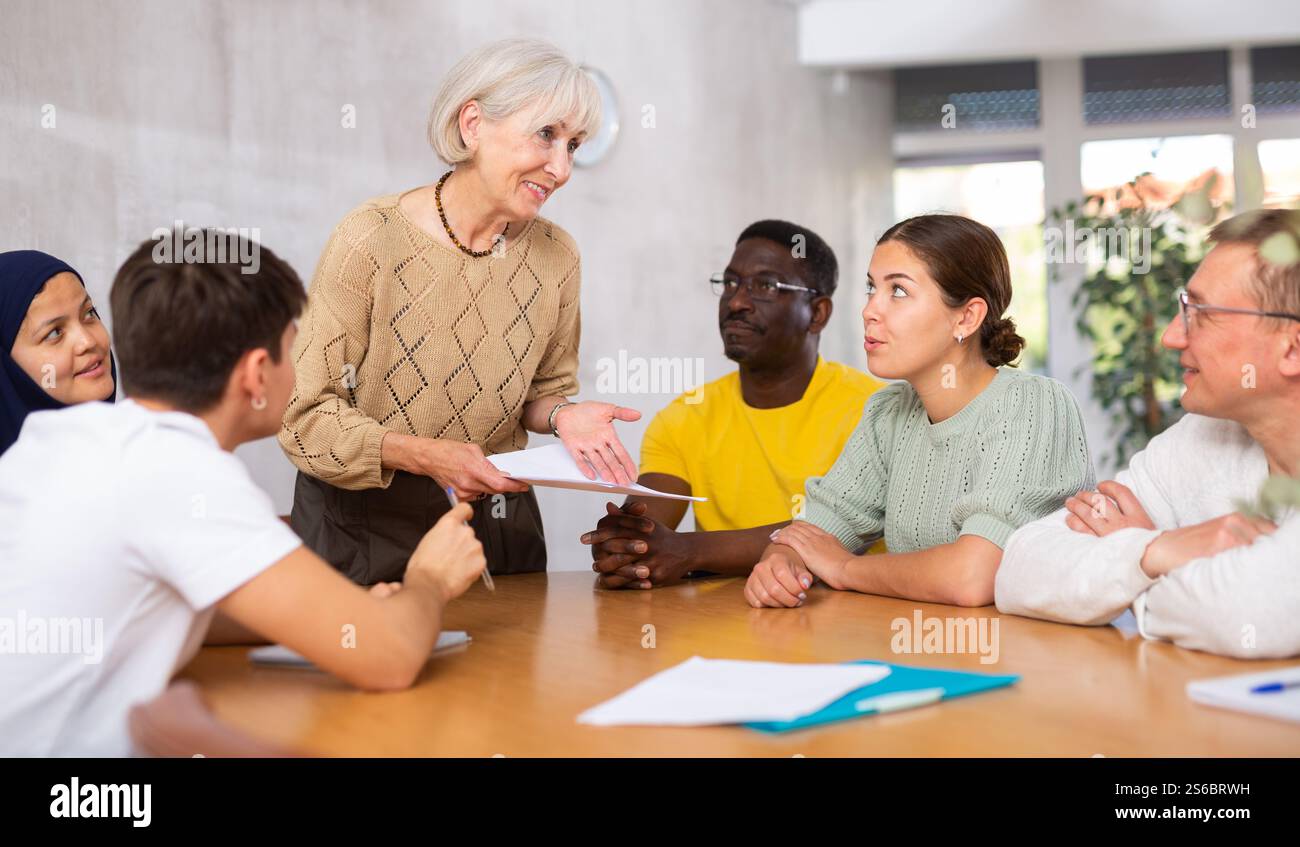 Elderly manager holds round table meetings for employees of different ...