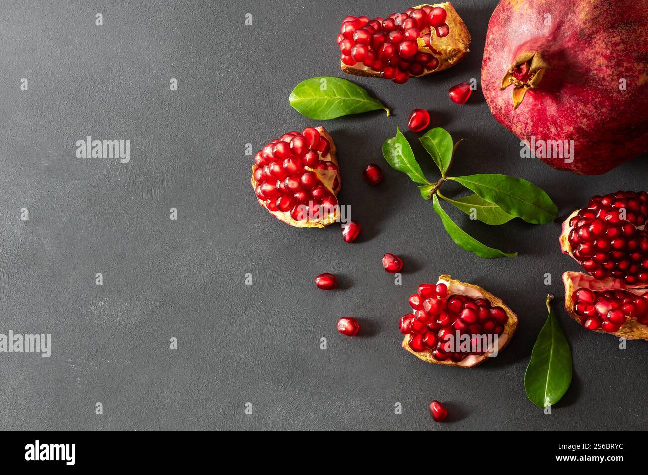 Fresh ripe whole and split juicy pomegranate with seeds and leaves on ...