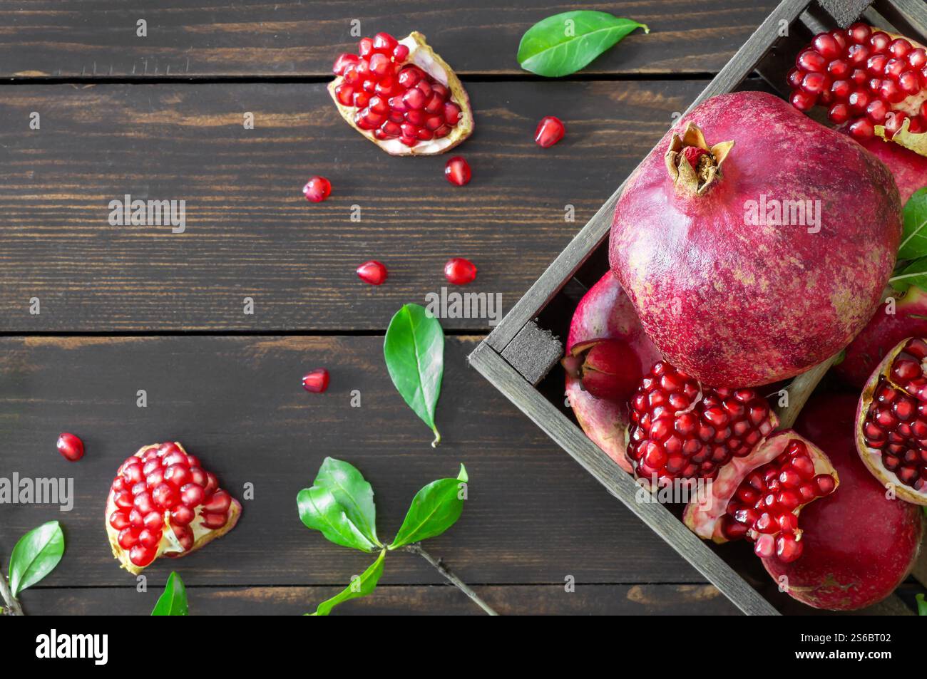 Fresh ripe whole and split juicy pomegranate with seeds and leaves on ...