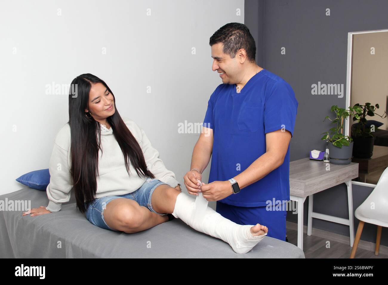 Woman with broken leg in a cast in the office of a dark-skinned Latino ...