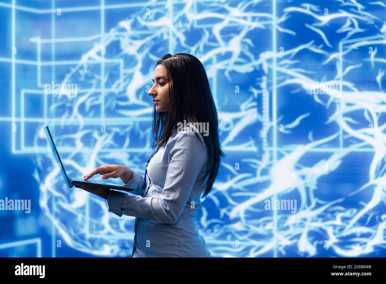 Programmer uses laptop to analyze AI models with large digital brain displayed behind. IT ...