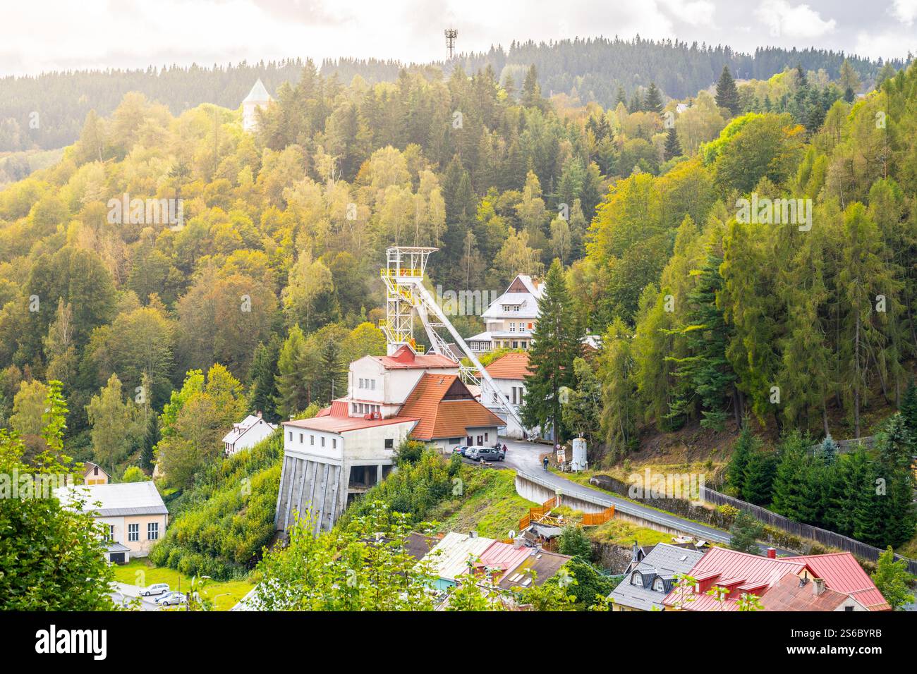 A historic mining tower rises against the backdrop of lush forests in ...