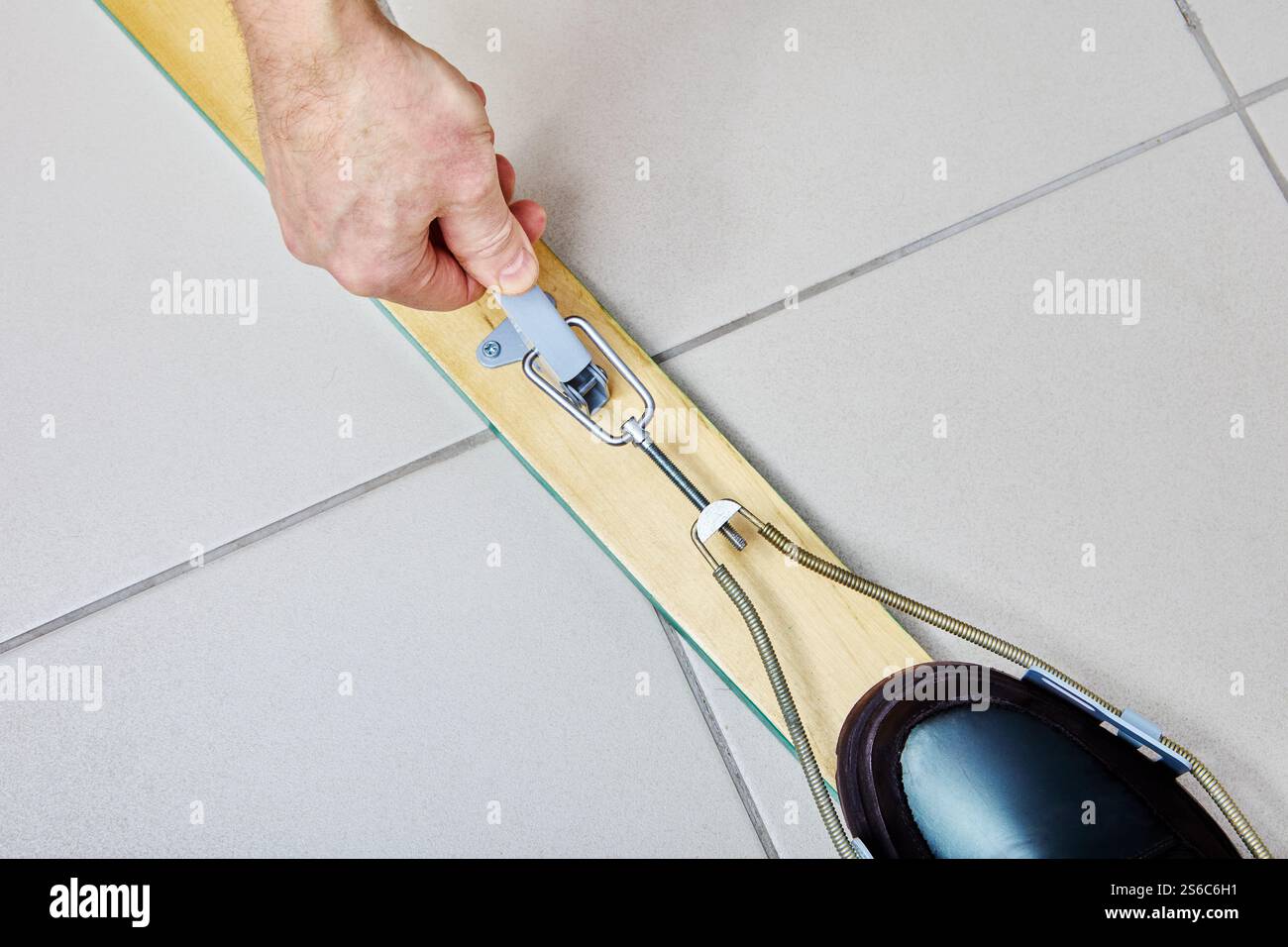 Skier tensions spring of cable ski bindings during installation and ...