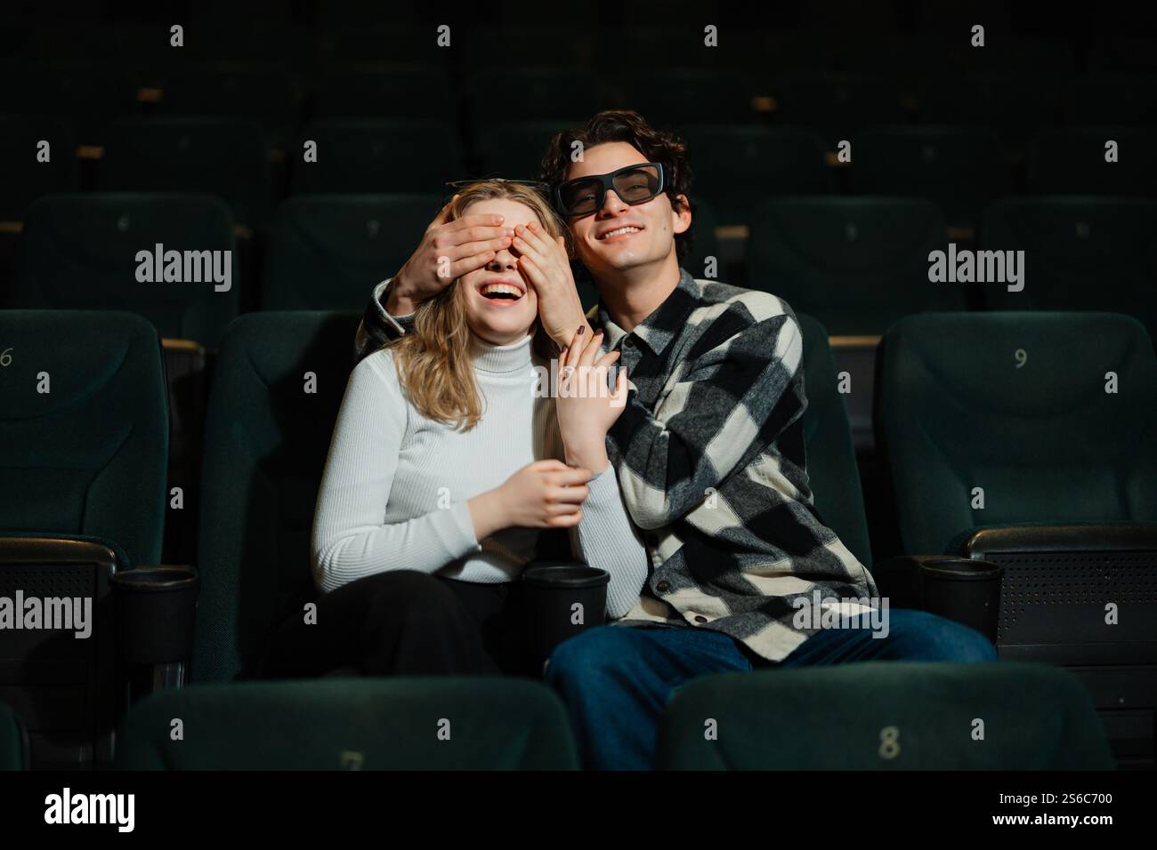Couple enjoying a playful moment in a movie theater at night Stock ...