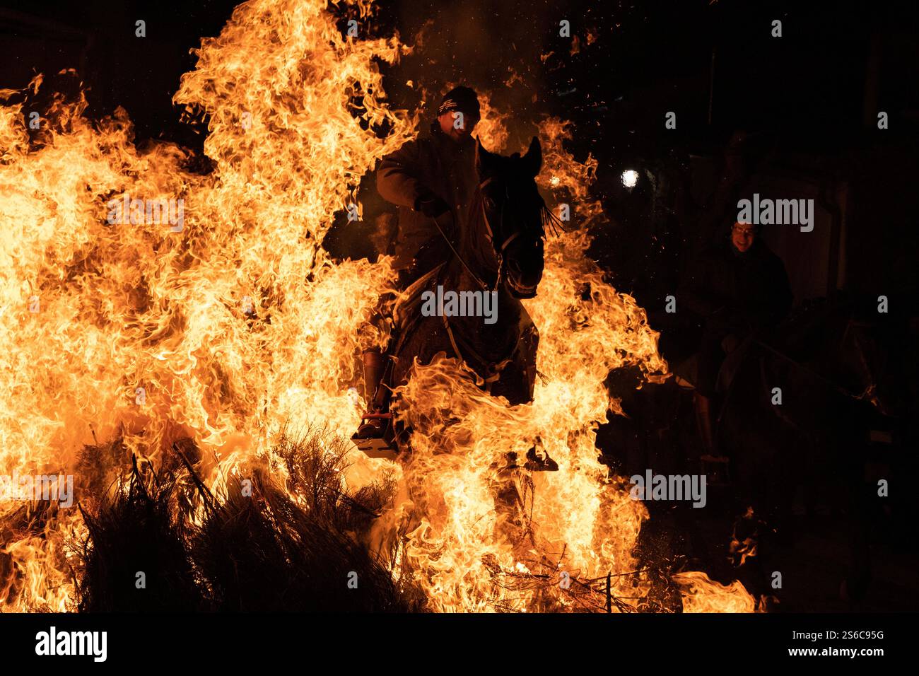 A horse jumps over a bonfire during the celebration of the Luminarias ...