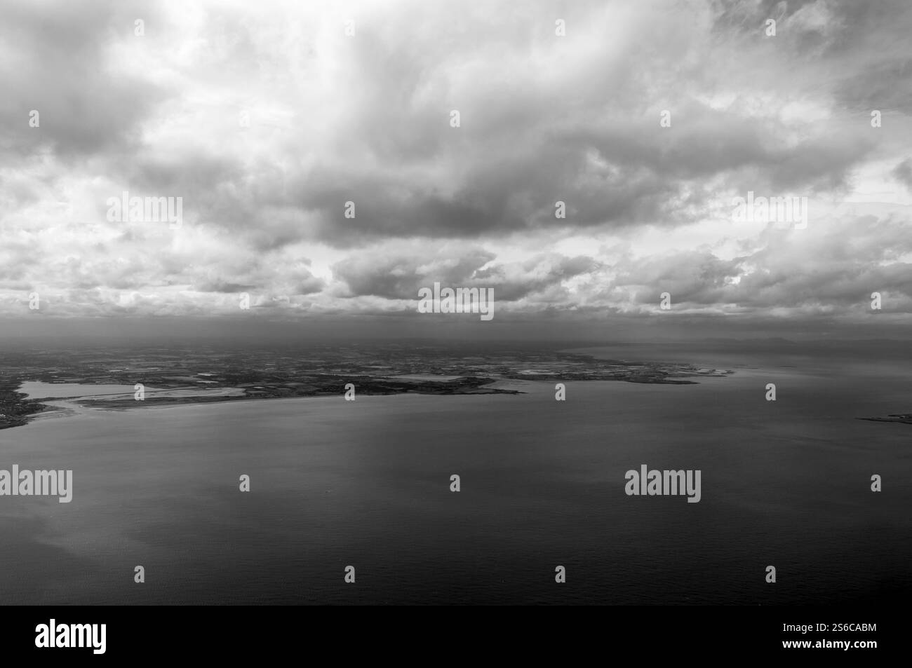 A black and white photo of a cloudy sky over a large body of water ...