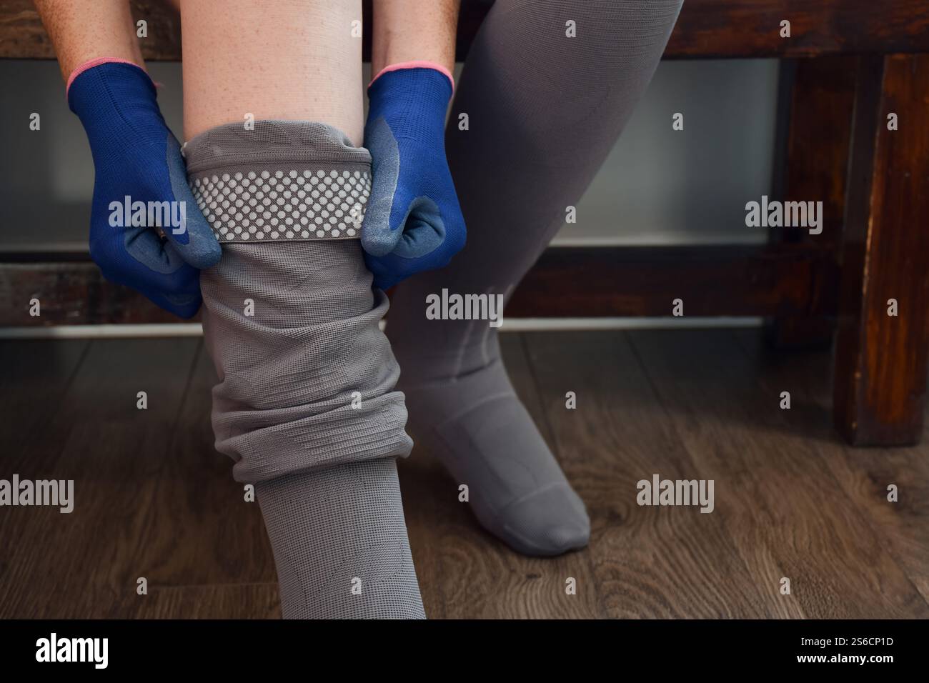 Woman putting on compression stockings using donning gloves closeup ...