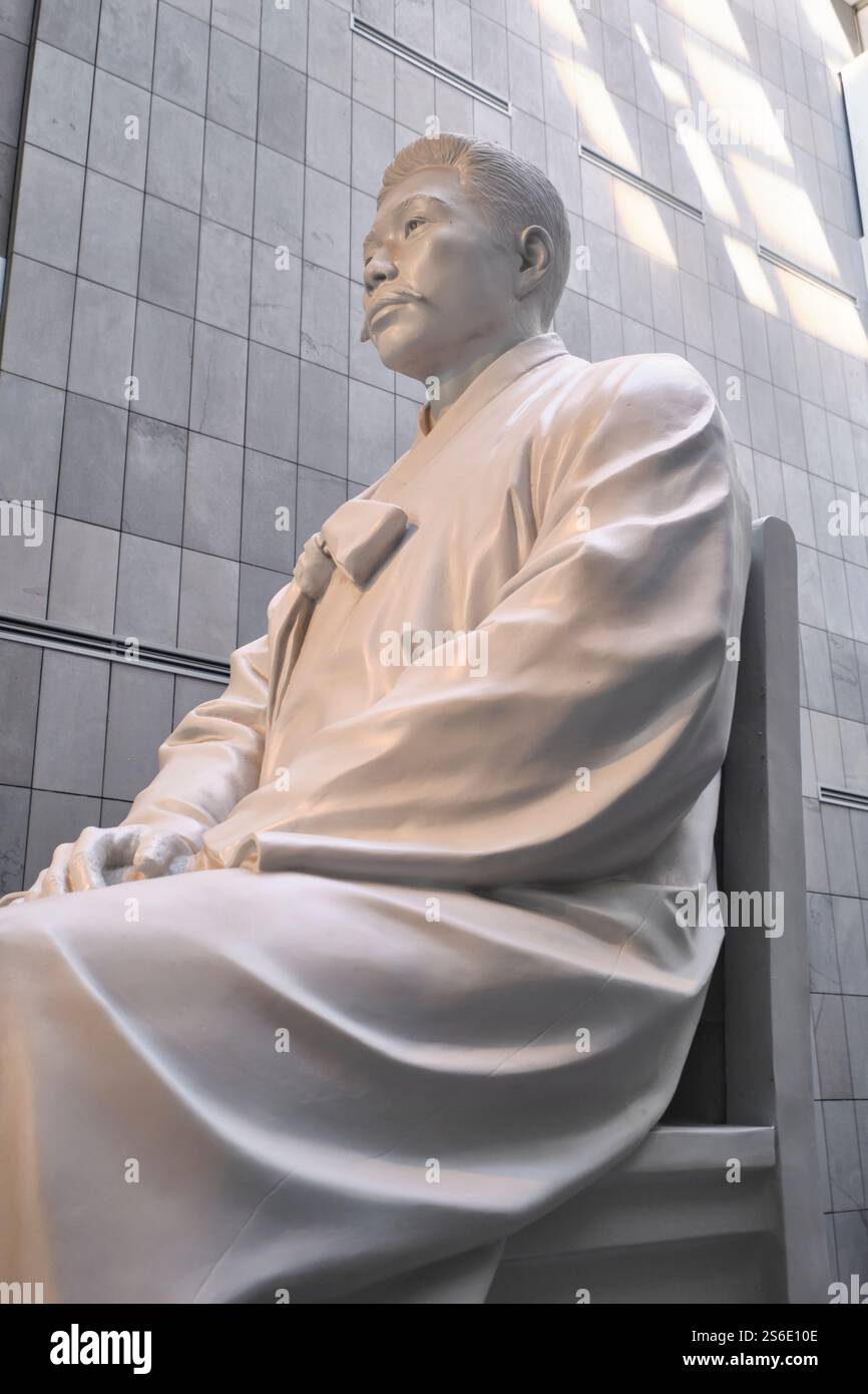 A large, white statue, sculpture of a sitting, somber Ahn Jung-geun ...