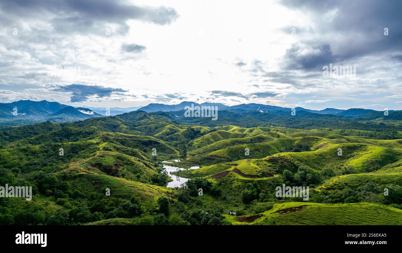 Landscape with mountains and clouds with green hills and a lake ...