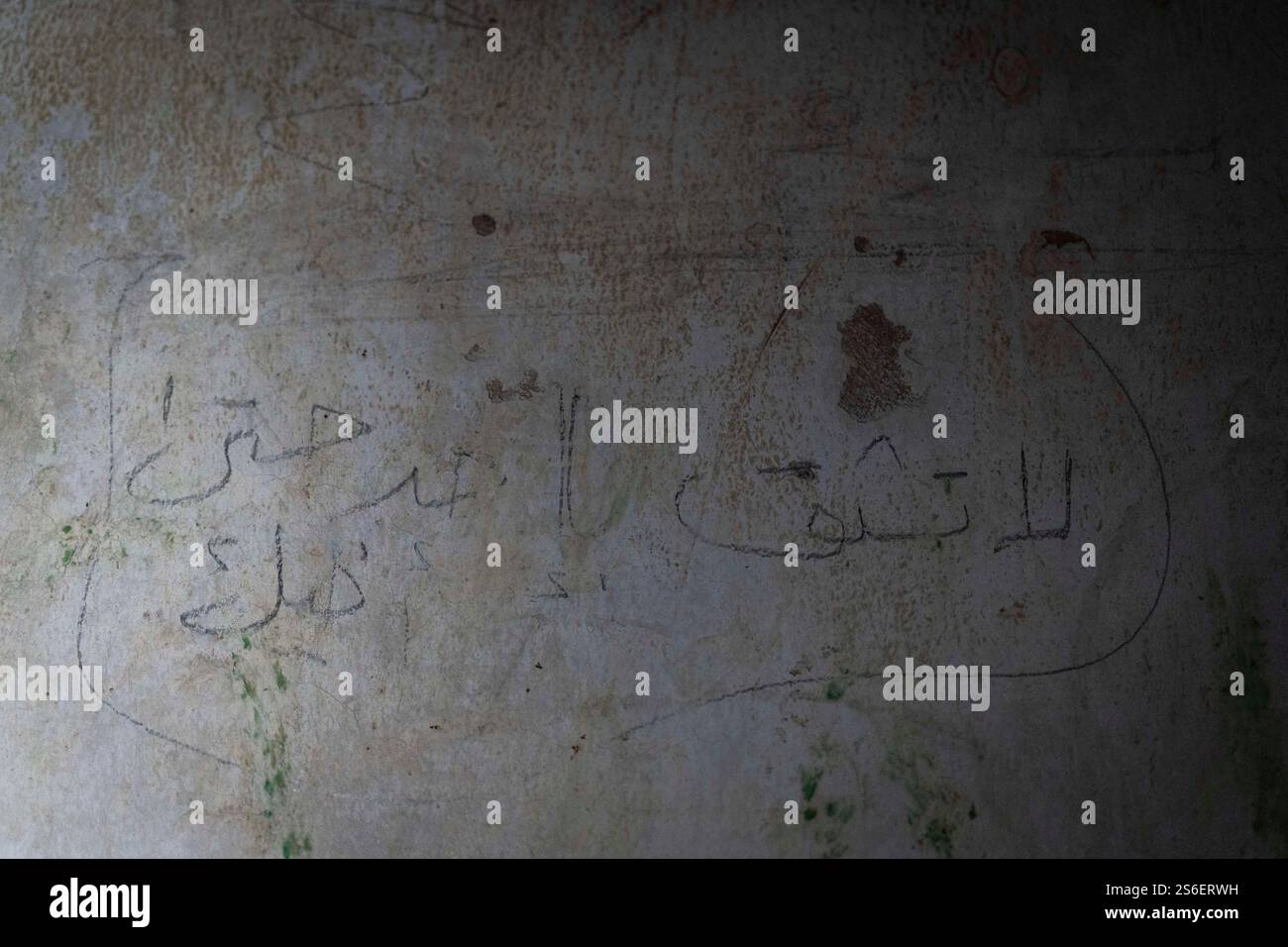 A graffiti in Arabic on the wall of a prison cell reads "Trust no one ...